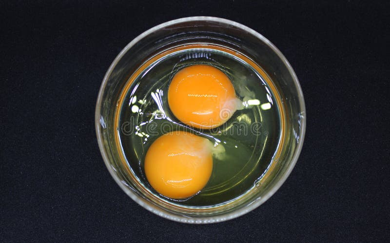 Two Raw Eggs in a Glass Bowl on Black Surface Top View Stock Image ...
