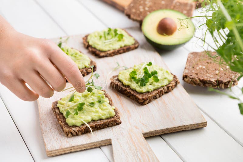 Preparing Snacks with Avocado Spread and Microgreen Stock Photo - Image ...