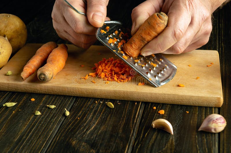 Preparing a Vegetable Dish. Chef Hands Grate Raw Carrots with a Grater ...