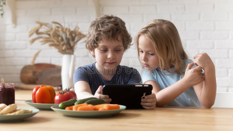 Preschool Children Seated at Table in Kitchen Using Tablet Computer ...