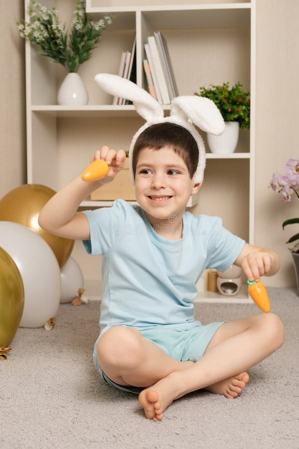 A Preschool Easter Boy Plays with Carrots, Rabbit Ears on His Head ...