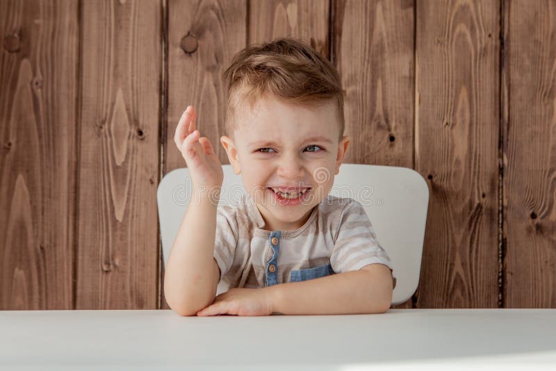 A Pretty Boy is Sitting at the Table, Raised His Hand Up. Close-up ...