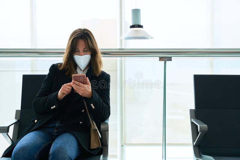 Pretty Brunette Girl With Protective Mask Looks At The Mobile Stock