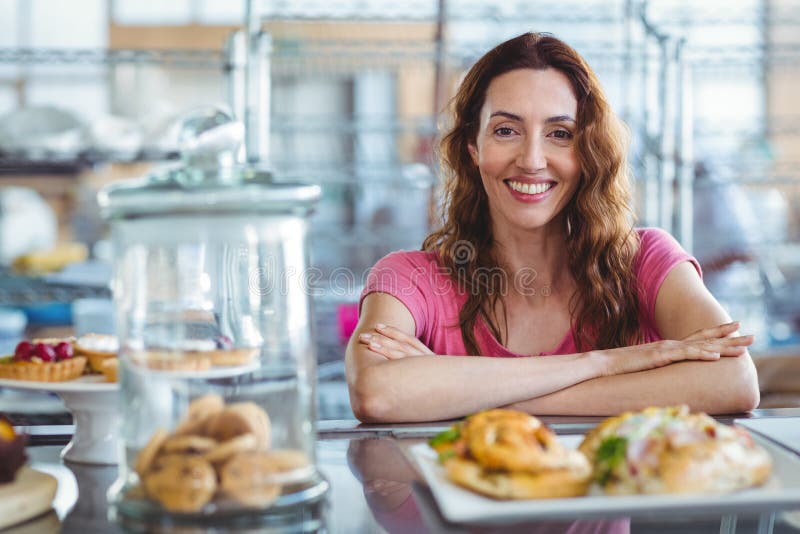 Pretty Brunette Smiling at Camera Behind Counter Stock Photo - Image of ...