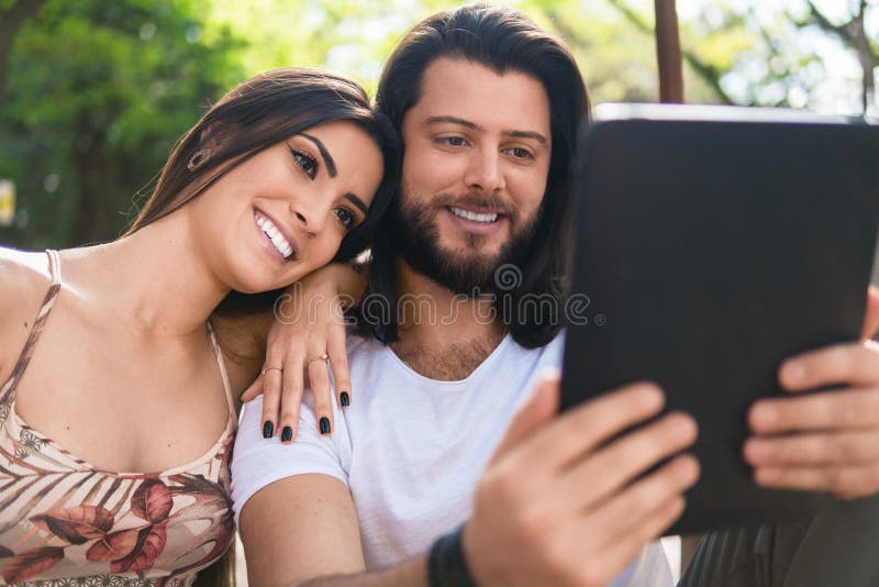 Pretty Couple Using Tablet for Entertainment in the Park Stock Photo ...