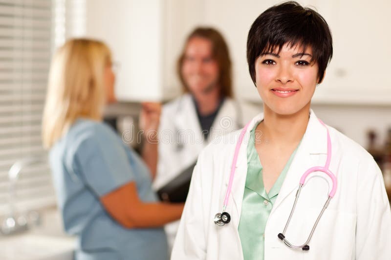 Pretty Doctor Smiles at Camera As Colleagues Talk Stock Image - Image ...