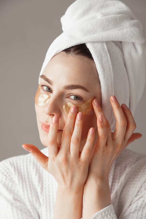 Pretty European Girl Applying Golden Collagen Patches Under Her Eyes