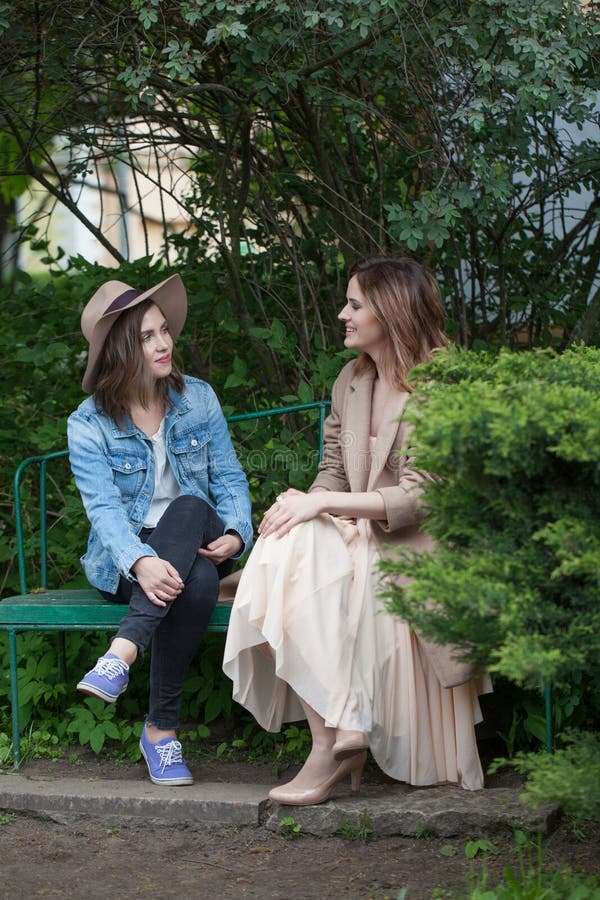 Pretty Friends Talking and Sitting on a Park Bench Outdoors Stock Photo ...