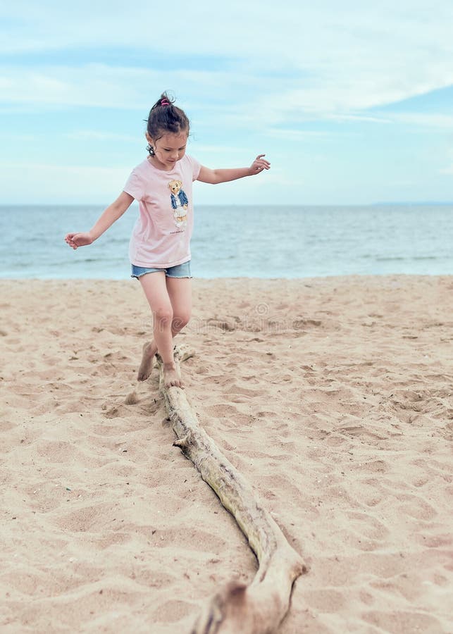 Pretty Girl Balancing on a Thick Branch Lying at the Beach Stock Photo ...