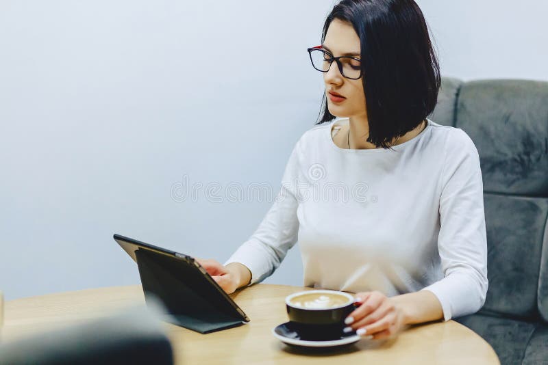 Girl in Cafe Drinks Coffee and Works on Tablet Stock Photo - Image of ...