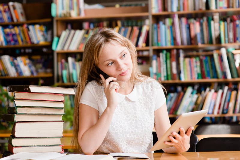 Pretty Girl in Library Using Tablet Computer and Talking on the Phone ...
