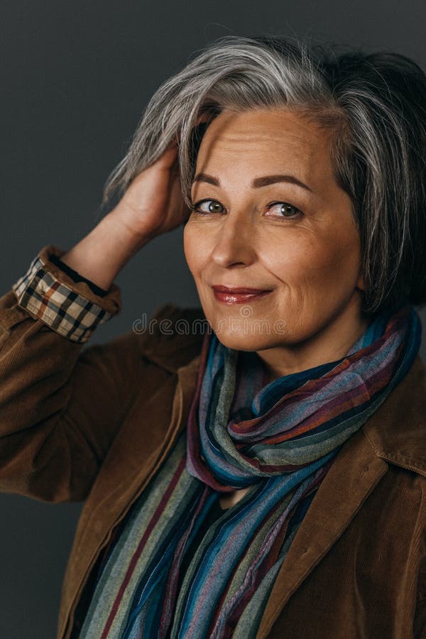 Gray Haired Mature Woman Smiles Holding Hands In Pockets While Looking