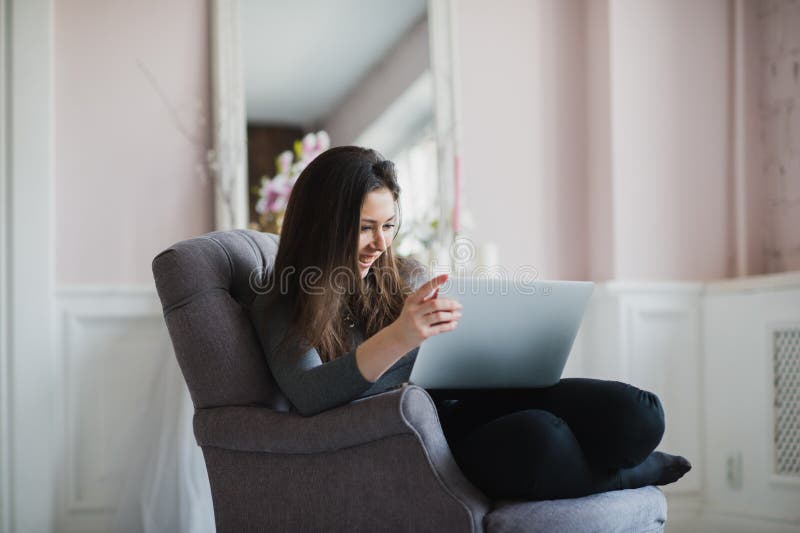Pretty Lady Working on Her Laptop while Sitting in an Armchair Stock ...