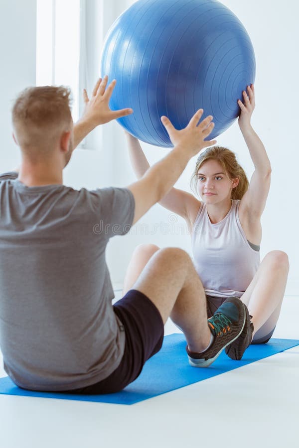 Patient Sitting on the Blue Mat in the Gym and Training with the Ball ...