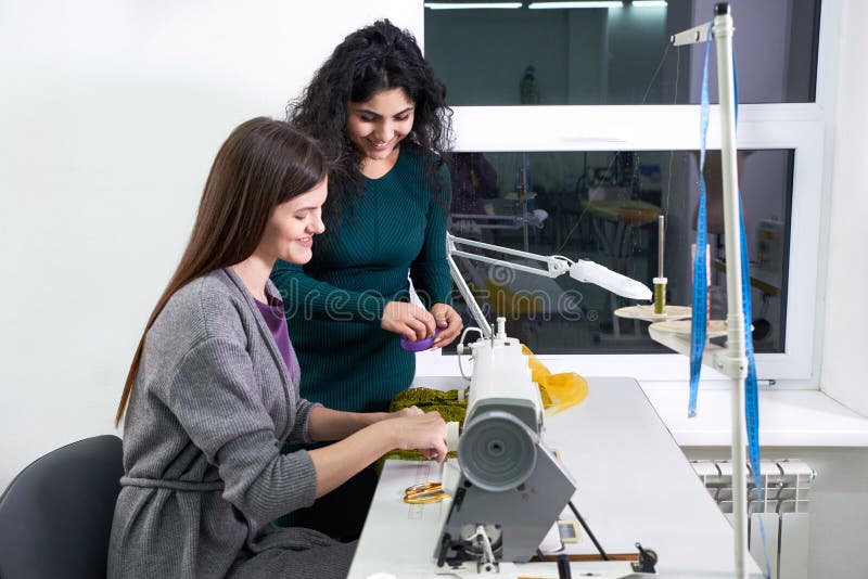 Pretty Seamstress Teaching Girl Working with Sewing Machine at Sewing ...