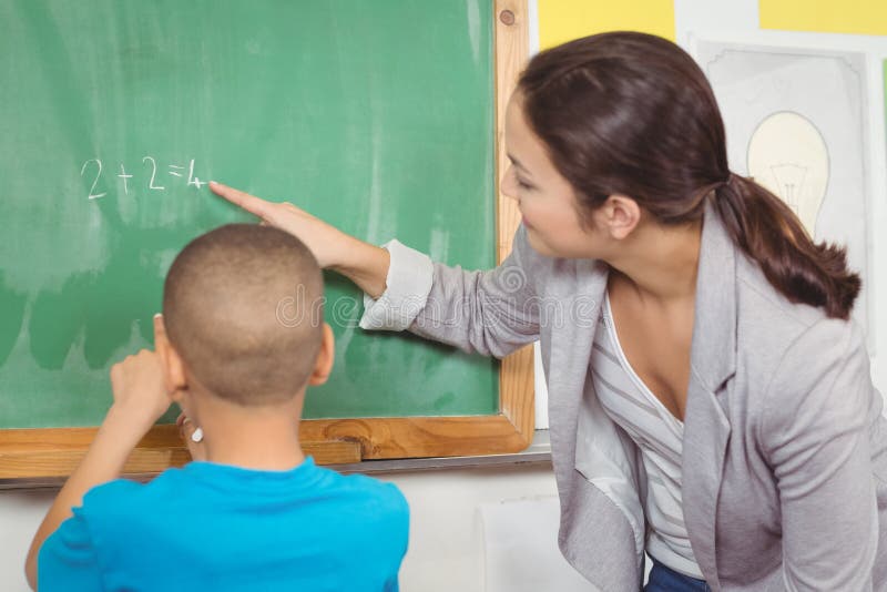 Pretty Teacher Helping Pupil at Chalkboard Stock Photo - Image of ...