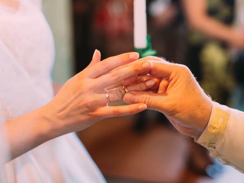The Priest is Putting the Wedding Ring on the Hand of the Bride. Stock ...