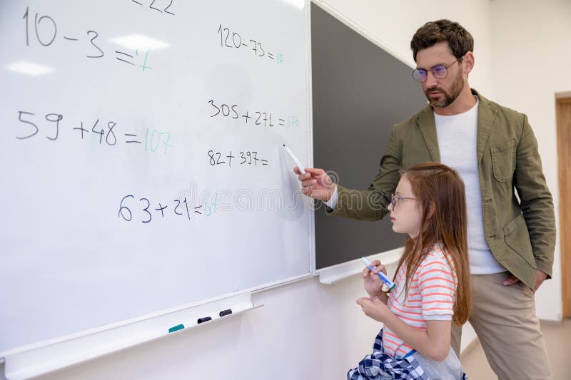 School Teacher Helping Pupil Writing on White Board Solving Math ...