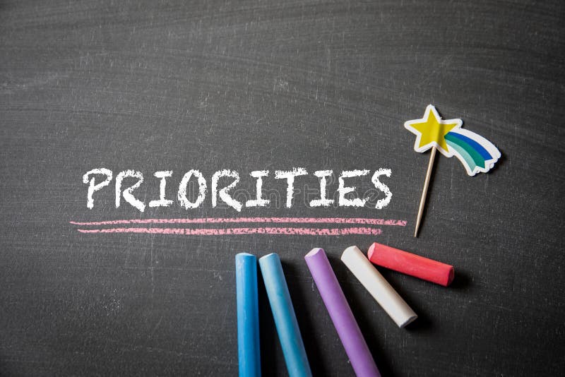 PRIORITIES. Text and Colored Pieces of Chalk on a Blackboard Background ...
