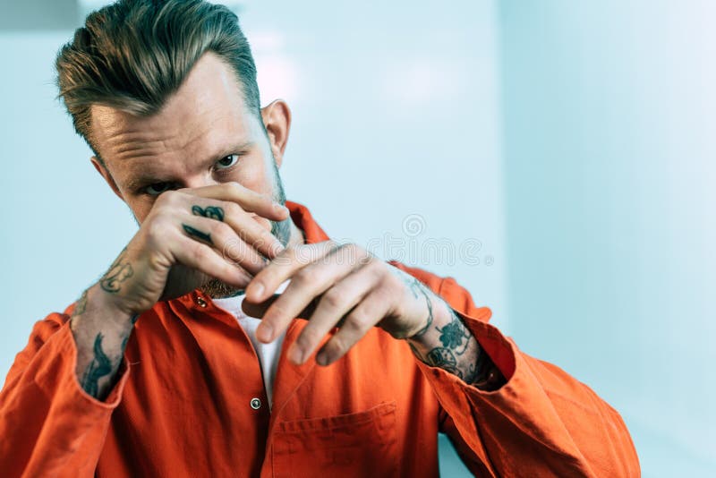 Prisoner with Tattoos Covering Face with Hands and Looking Stock Image ...
