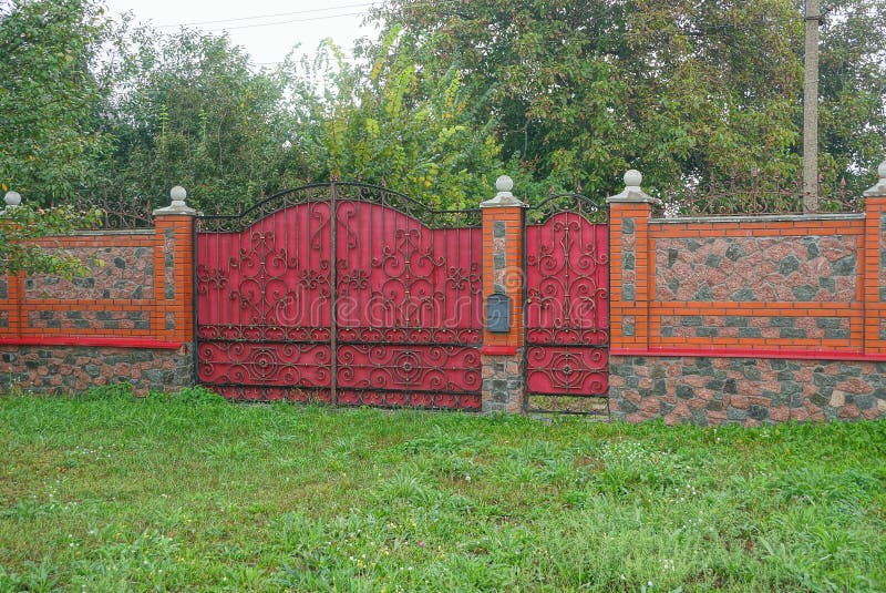 Red Iron Gate with a Wrought-iron Pattern with a Stone Fence in the ...