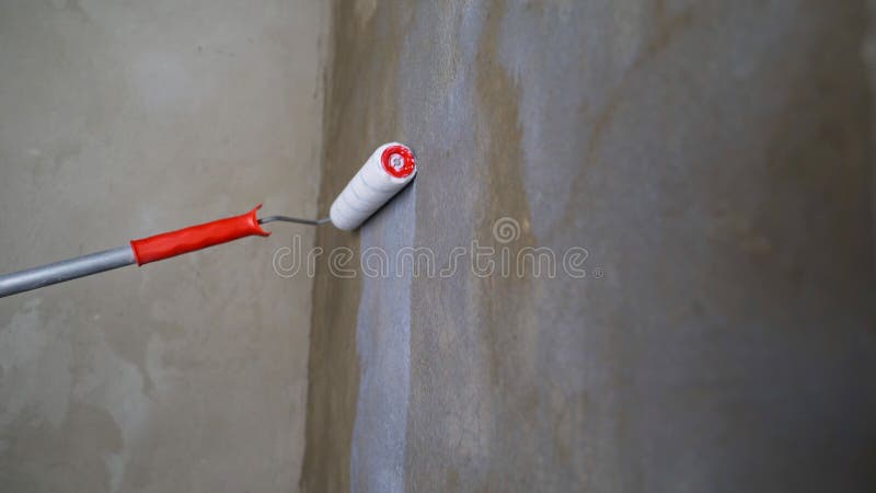 The Process of Applying a Primer To a Concrete Wall Using a Roller. the ...