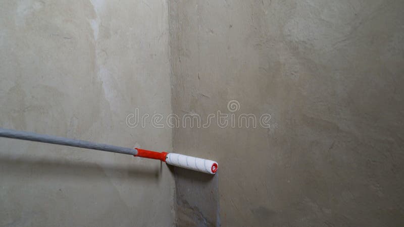 The Process of Applying a Primer To a Concrete Wall Using a Roller. the ...