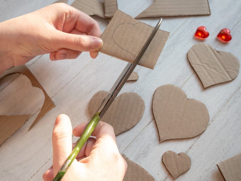 The Process of Cutting Out Hearts with Scissors from Cardboard. the ...