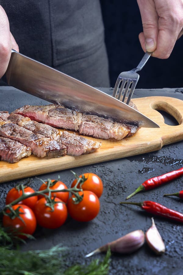 The Process of Cutting a Steak into Pieces. Chef with Fork and Knife ...
