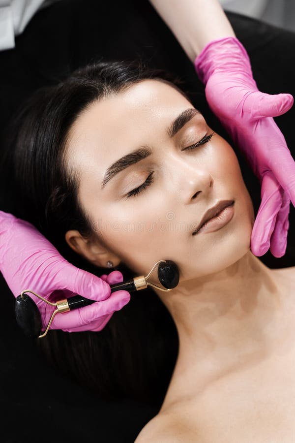 Process Of Face Massage With Black Stone Roller Close Up Cosmetologist