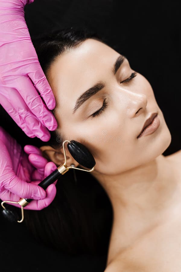 Process Of Face Massage With Black Stone Roller Close Up Cosmetologist