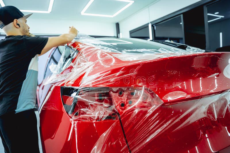 The Process of Installing Protective Film on the New Red Car. Stock ...