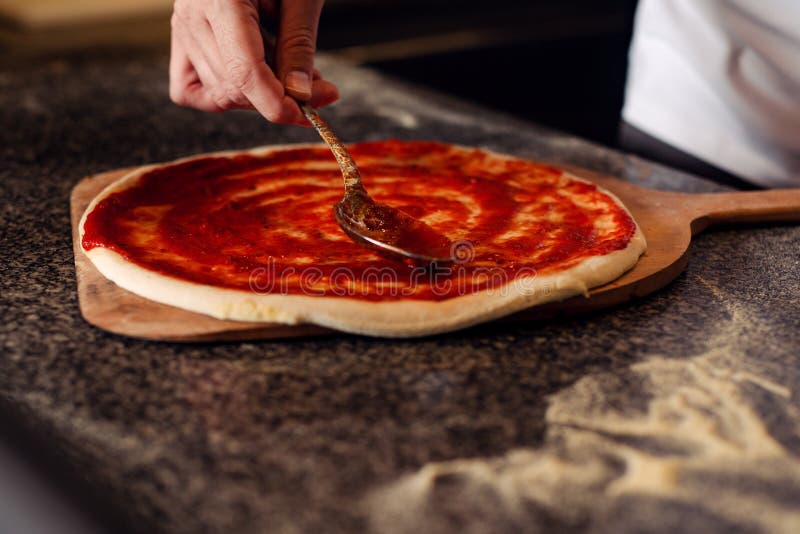 The Process of Preparing Pizza. the Chef Pours Tomato Sauce Over the ...