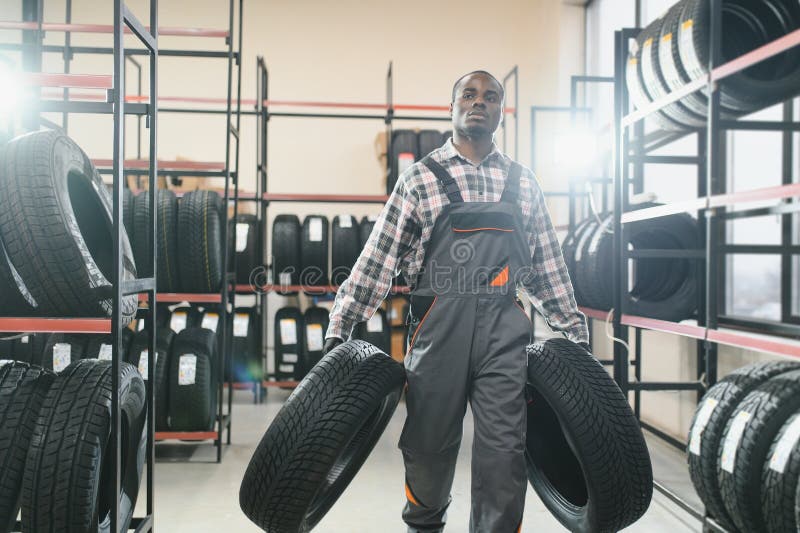 Professional African American Worker with Tire. Man is in the Tire ...