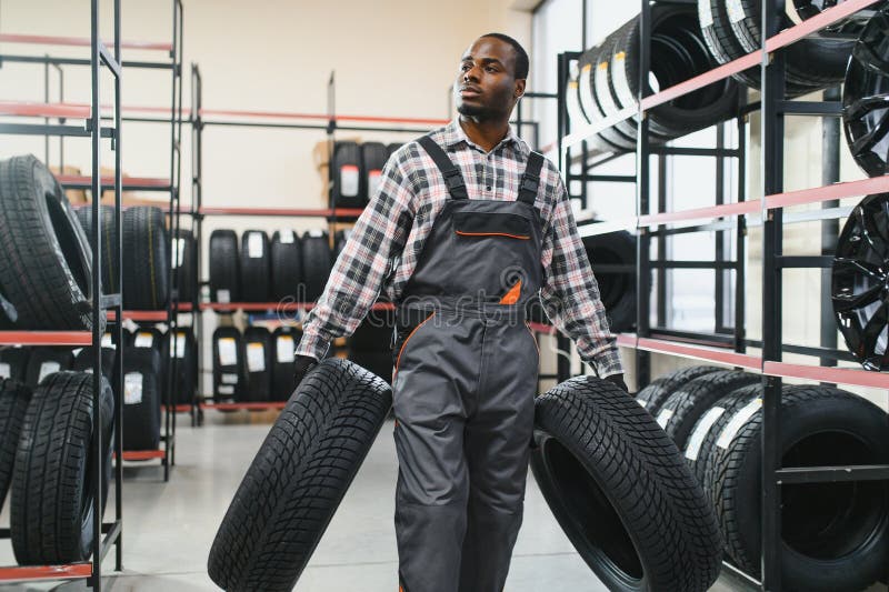 Professional African American Worker with Tire. Man is in the Tire ...