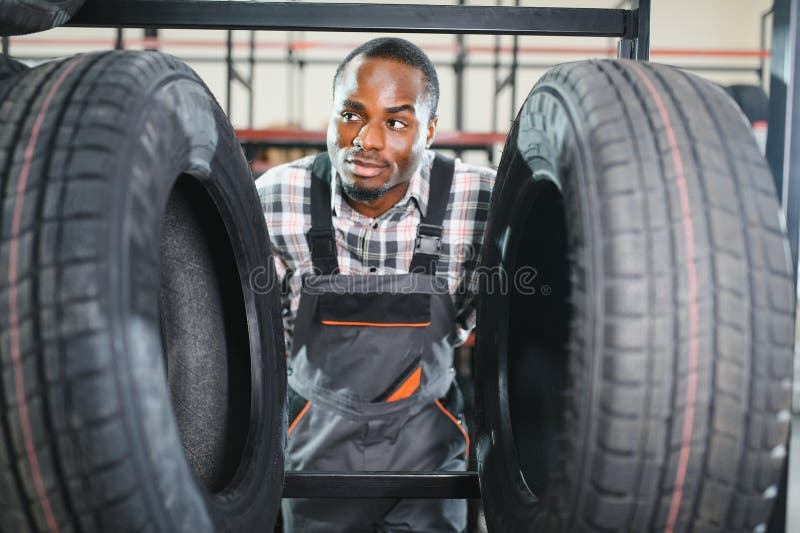 Professional African American Worker with Tire. Man is in the Tire ...