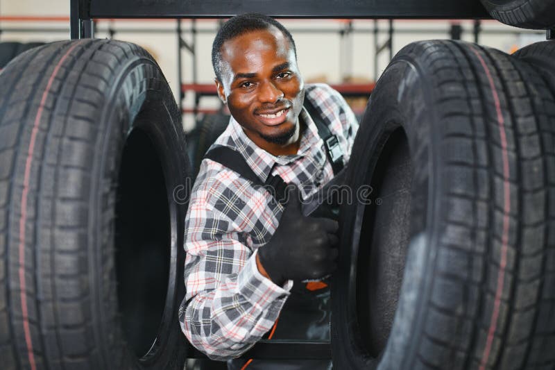 Professional African American Worker with Tire. Man is in the Tire ...