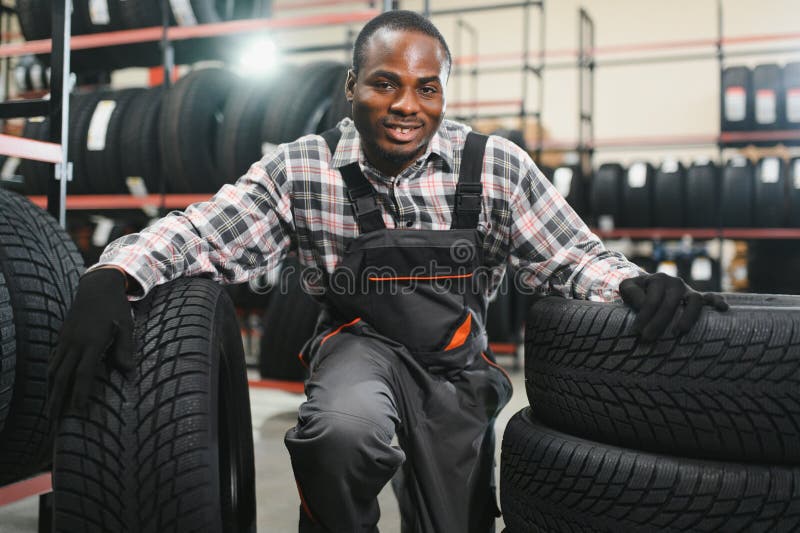 Professional African American Worker with Tire. Man is in the Tire ...