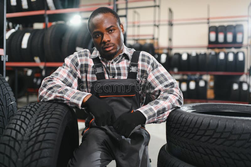Professional African American Worker with Tire. Man is in the Tire ...
