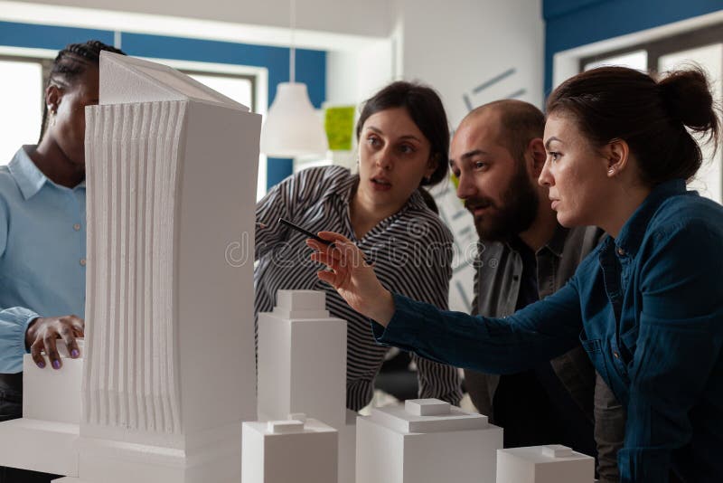 Professional Architect with Working Partners Pointing at Skyscraper ...