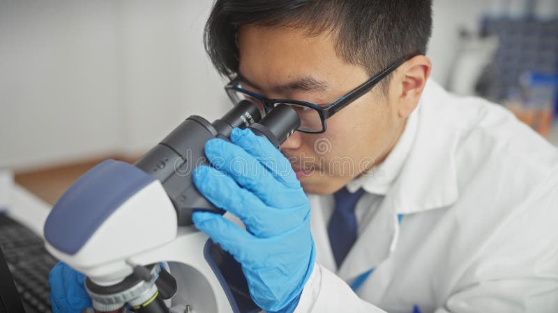 A Professional Asian Man in a White Lab Coat Examines Samples with a ...