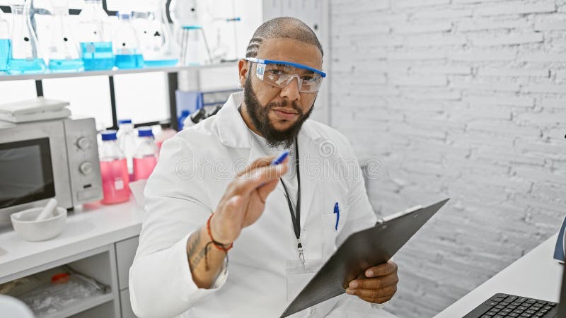 Professional Black Man in Lab Coat Holding a Clipboard in a Modern ...