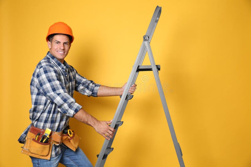 Professional Builder Climbing Up Metal Ladder on Yellow Background ...