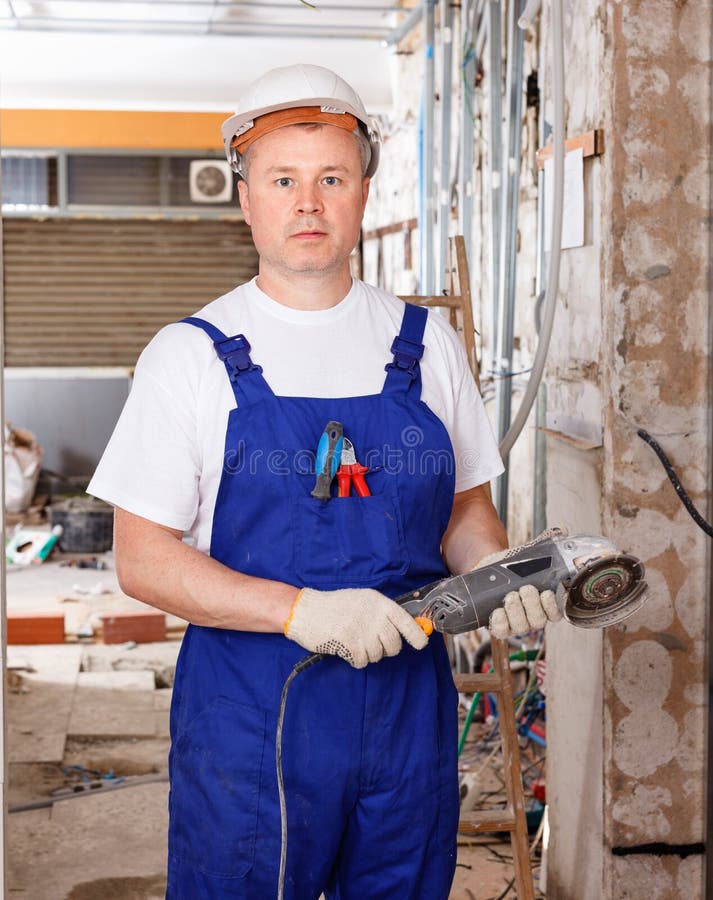 Professional Builder Handyman Working with Angle Drive Grinder Indoors ...