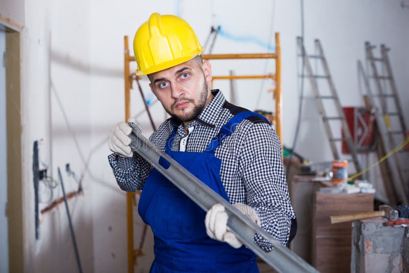 Professional Builder in Helmet is Looking at the Level of the Profile ...