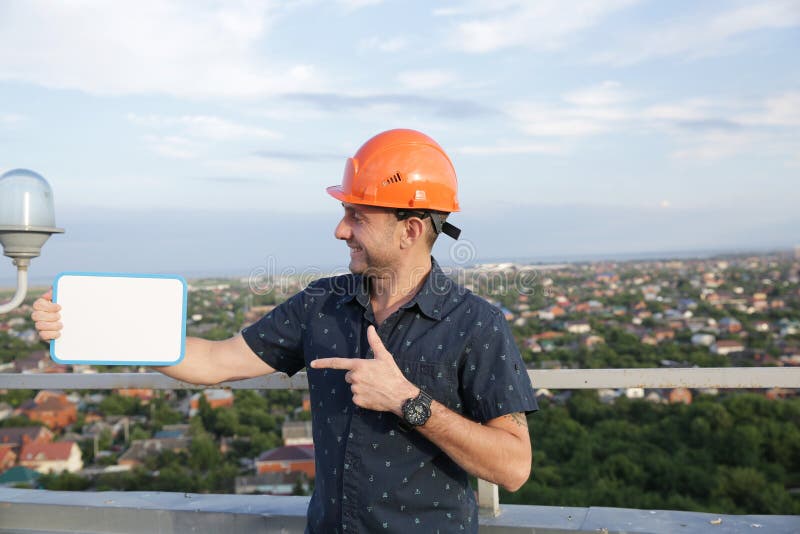 Builder in a Protective Helmet with a Tablet for Writing in His Hand is ...