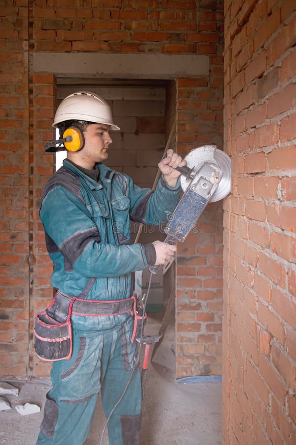 A Professional Builder in Work Clothes Works with a Cutting Tool Stock ...
