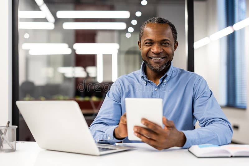Smiling Businessman Using Tablet and Laptop in Modern Office Stock ...
