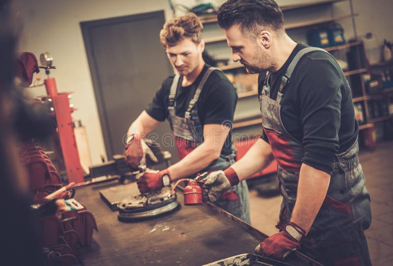 Professional Car Mechanics Working Under Lifted Car in Auto Repair ...