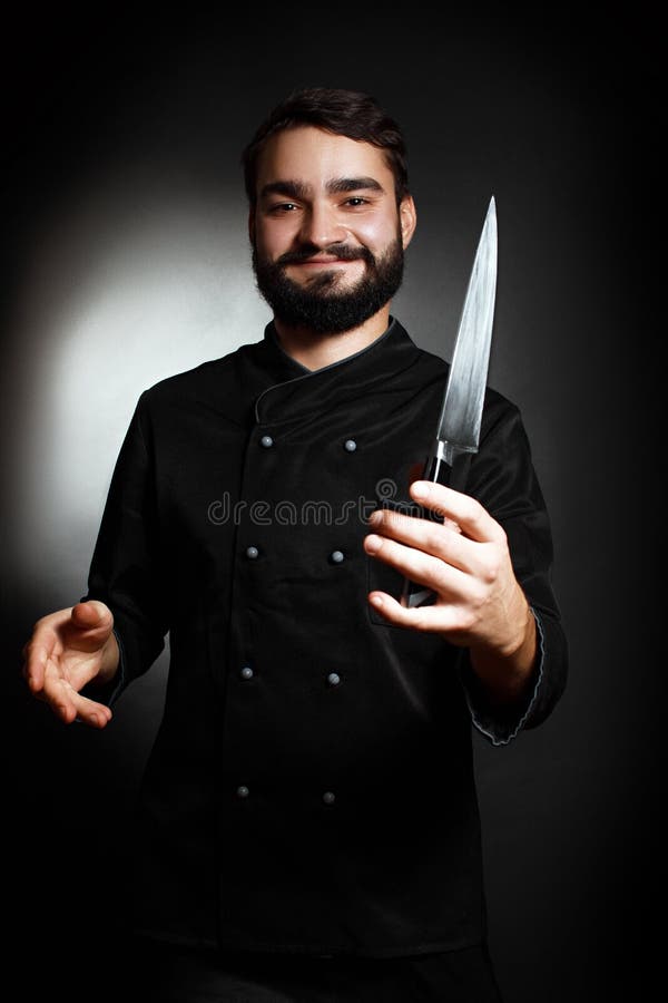 Professional Chef with a Beard in a Black Uniform with a Kitchen Knife ...